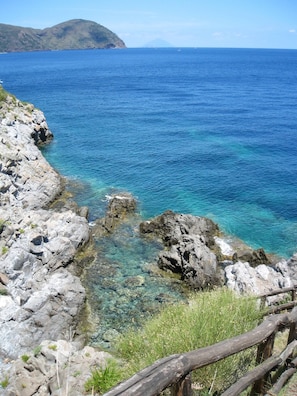 Paisagem costeira com falésias rochosas e mar azul cristalino.