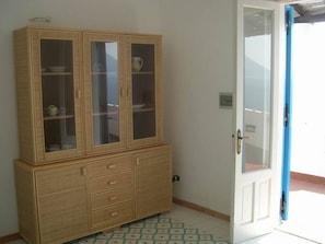 Um quarto com um armário de madeira com portas de vidro, uma porta branca com puxador azul e um chão estampado.