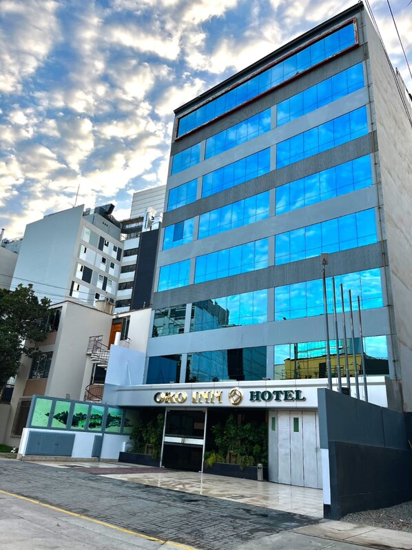 Um hotel moderno com fachada de vidro que reflete o céu.