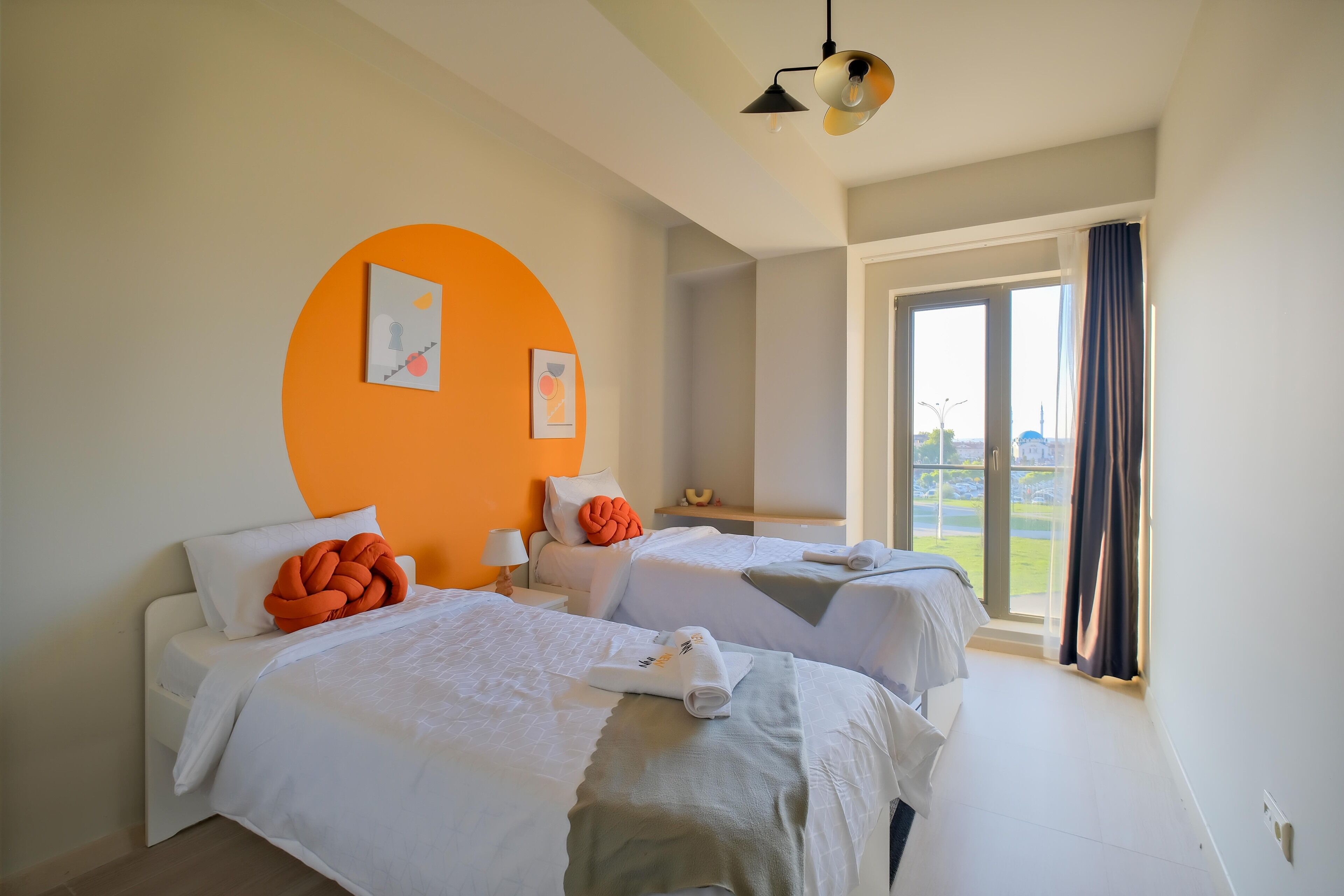 Quarto de hotel com duas camas, uma janela grande com cortinas e vista para o exterior.