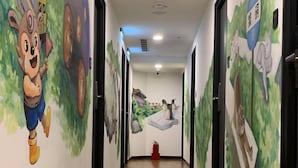 Corredor com piso de madeira e paredes decoradas com personagens de desenho animado e cenas da natureza.