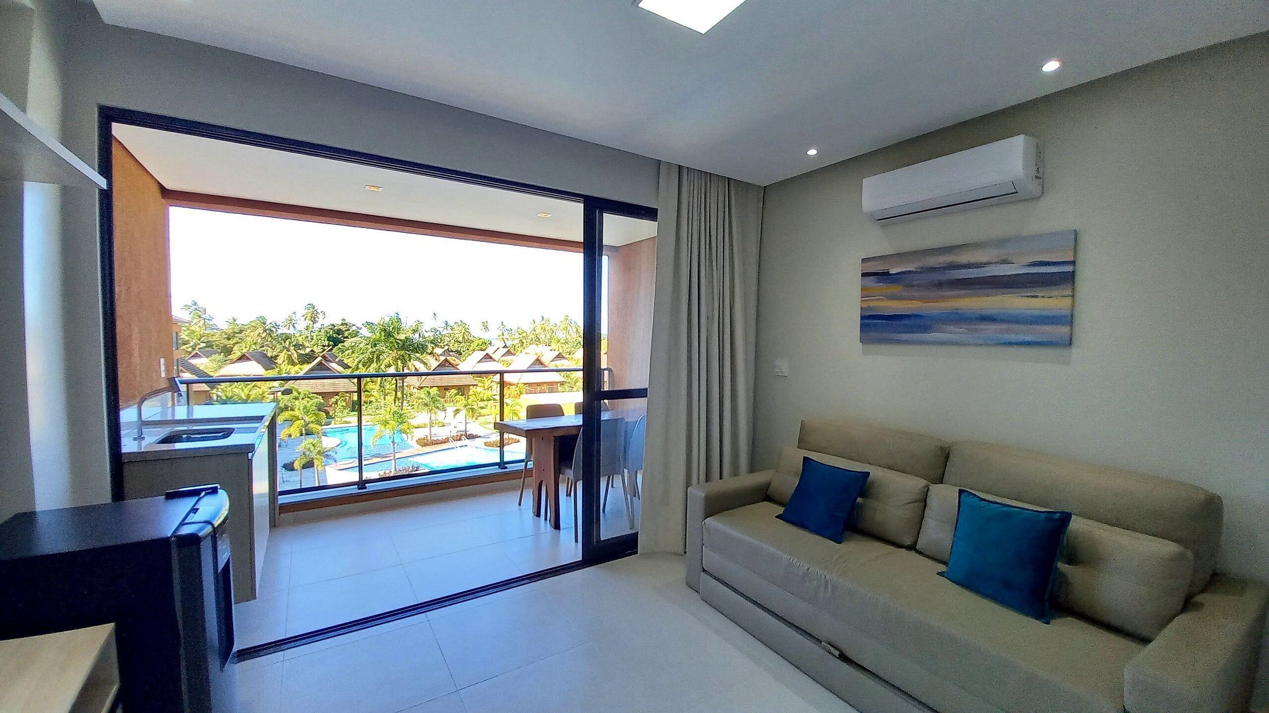 Uma sala de estar moderna com sofá, uma mesa de jantar e vista para uma piscina e área externa.