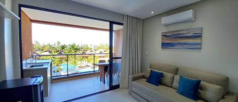 Uma sala de estar moderna com sofá, uma mesa de jantar e vista para uma piscina e área externa.