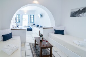 Uma sala de estar moderna e minimalista, com um sofá branco, uma mesa de centro de madeira e vista para uma varanda através de uma porta arqueada.