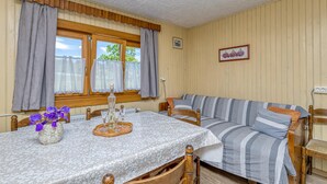 Um quarto aconchegante com uma mesa de jantar, um sofá e uma janela com cortinas.
