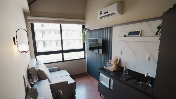 Cozinha compacta com micro-ondas embutido, pia e janela que proporciona iluminação natural.
