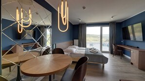 Quarto de hotel moderno com uma cama, uma escrivaninha, uma TV e varanda com vista.