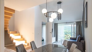 Uma área de refeições moderna com uma mesa de mármore, cadeiras e uma escada com degraus de madeira.