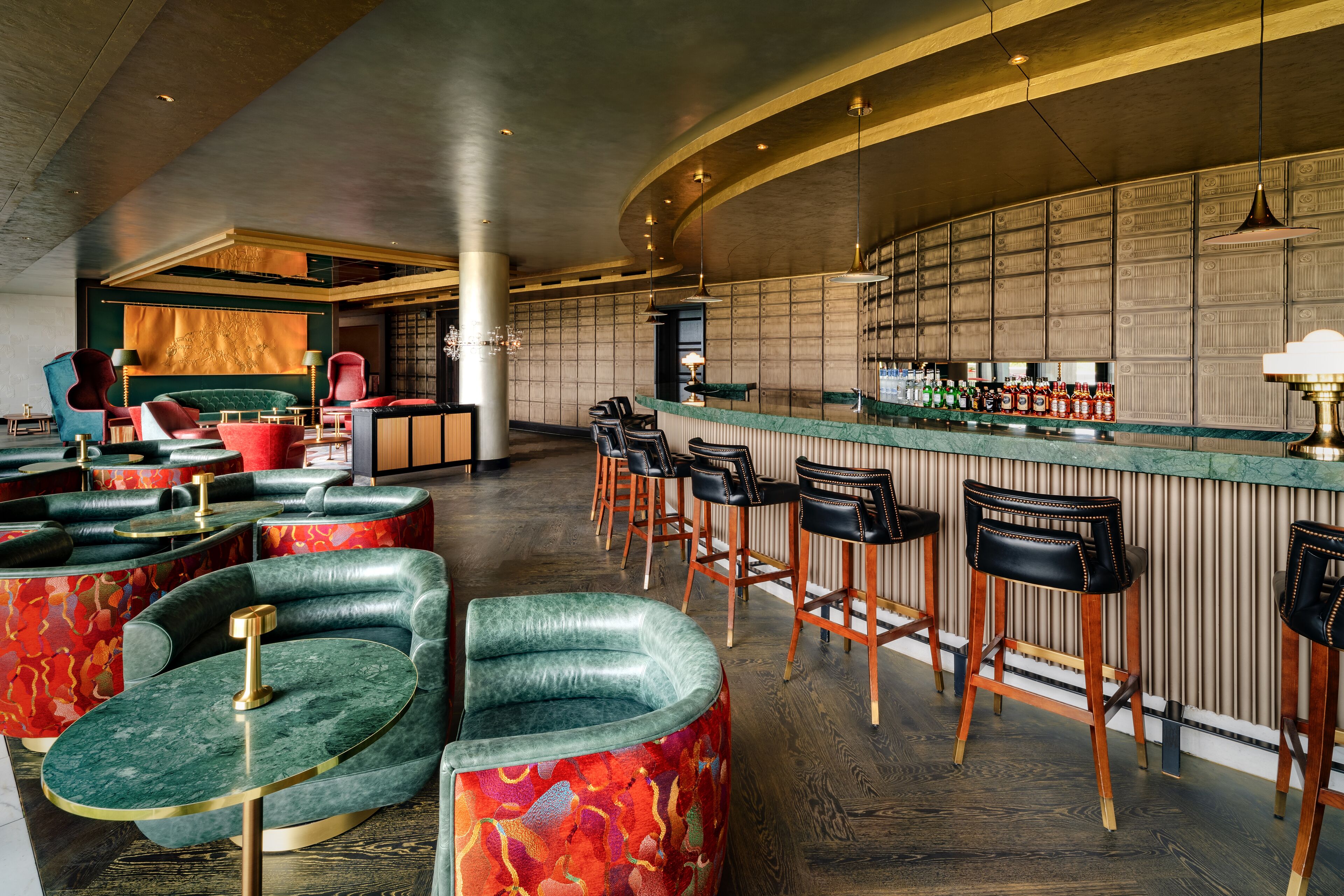 Uma área de bar moderna com balcão curvo, banquetas e um espaço de estar com mesas redondas e cadeiras.