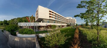 Um hotel moderno com fachada curva, várias varandas e um jardim bem cuidado.