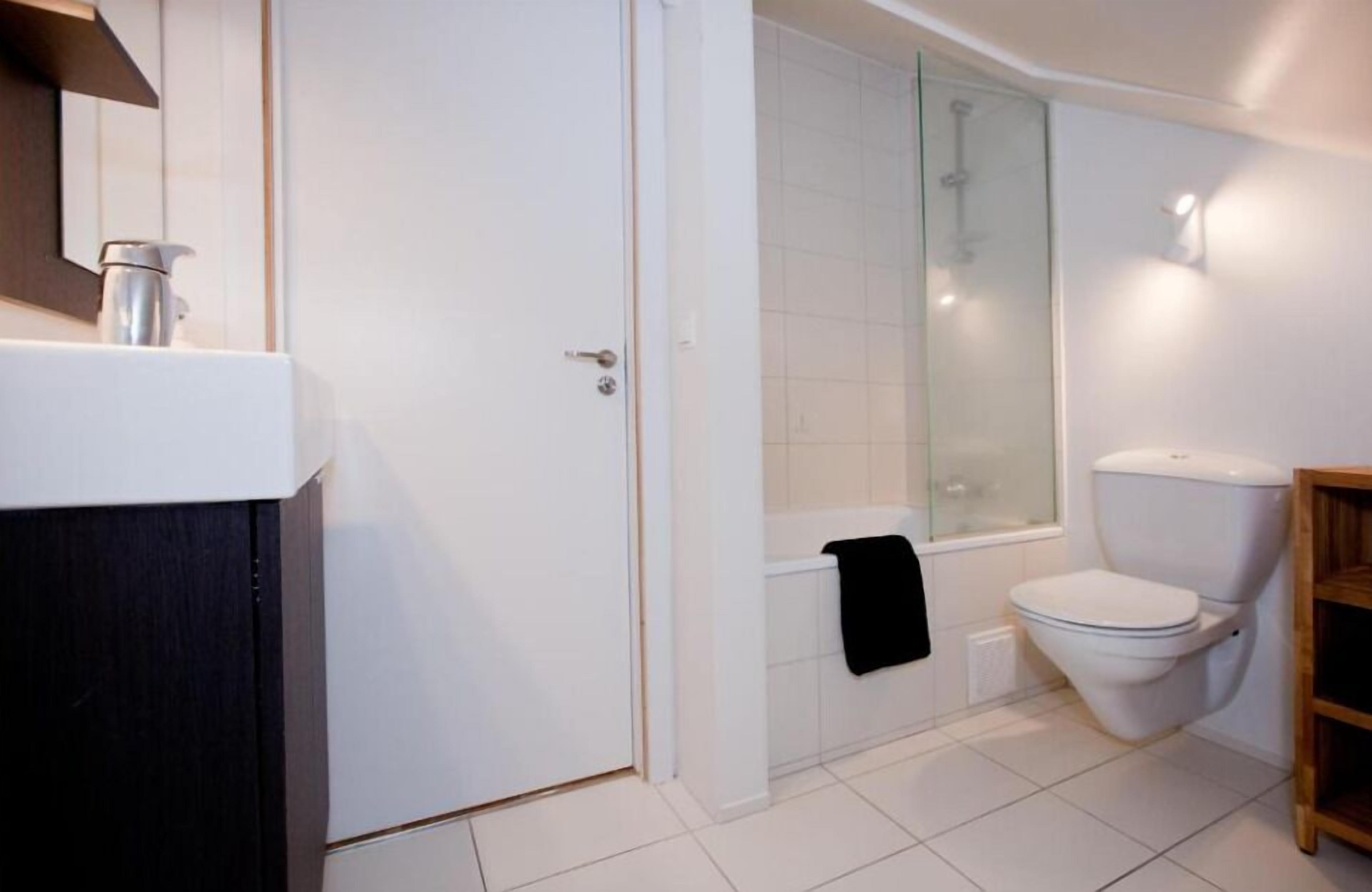 Uma casa de banho moderna com chuveiro, sanita e lavatório.