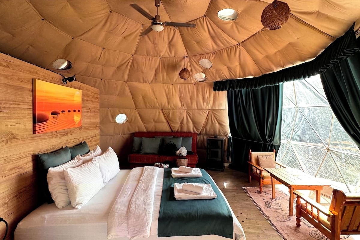 Um quarto aconchegante estilo tenda, com uma cama, uma mesinha e uma cadeira.
