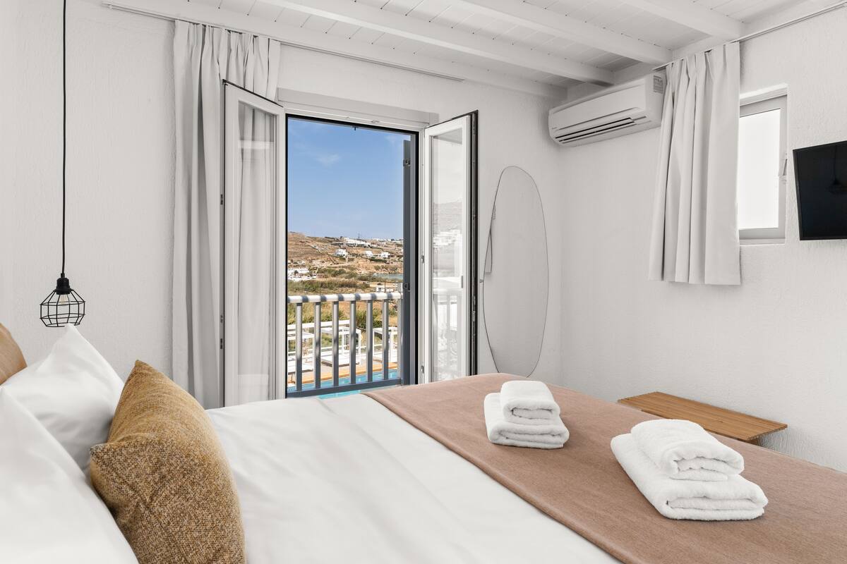 Quarto de hotel com cama, vista da paisagem e varanda.