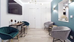 Quarto moderno com mesa de jantar, duas cadeiras, televisão e espelho.