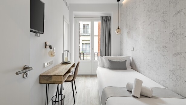 Quarto de hotel moderno com cama, escrivaninha e vista para a varanda externa.