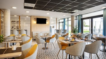 Um restaurante moderno com piso de padrão geométrico, mobiliário contemporâneo e amplas janelas que oferecem vista para o exterior.