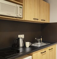 Uma cozinha compacta equipada com micro-ondas, chaleira, cafeteira e pia.
