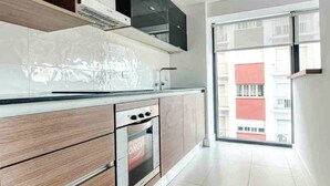 Uma cozinha moderna com armários de madeira, forno embutido e uma janela grande.