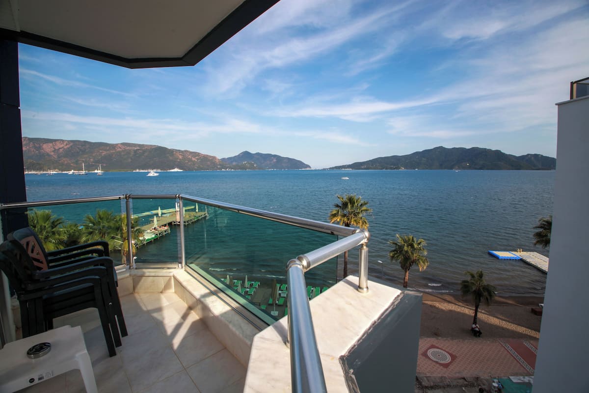 Uma varanda com vista para o mar, uma cadeira e uma mesa pequena.