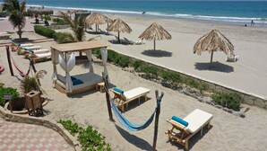 Um resort à beira-mar com espreguiçadeiras, guarda-sóis de palha e uma rede.