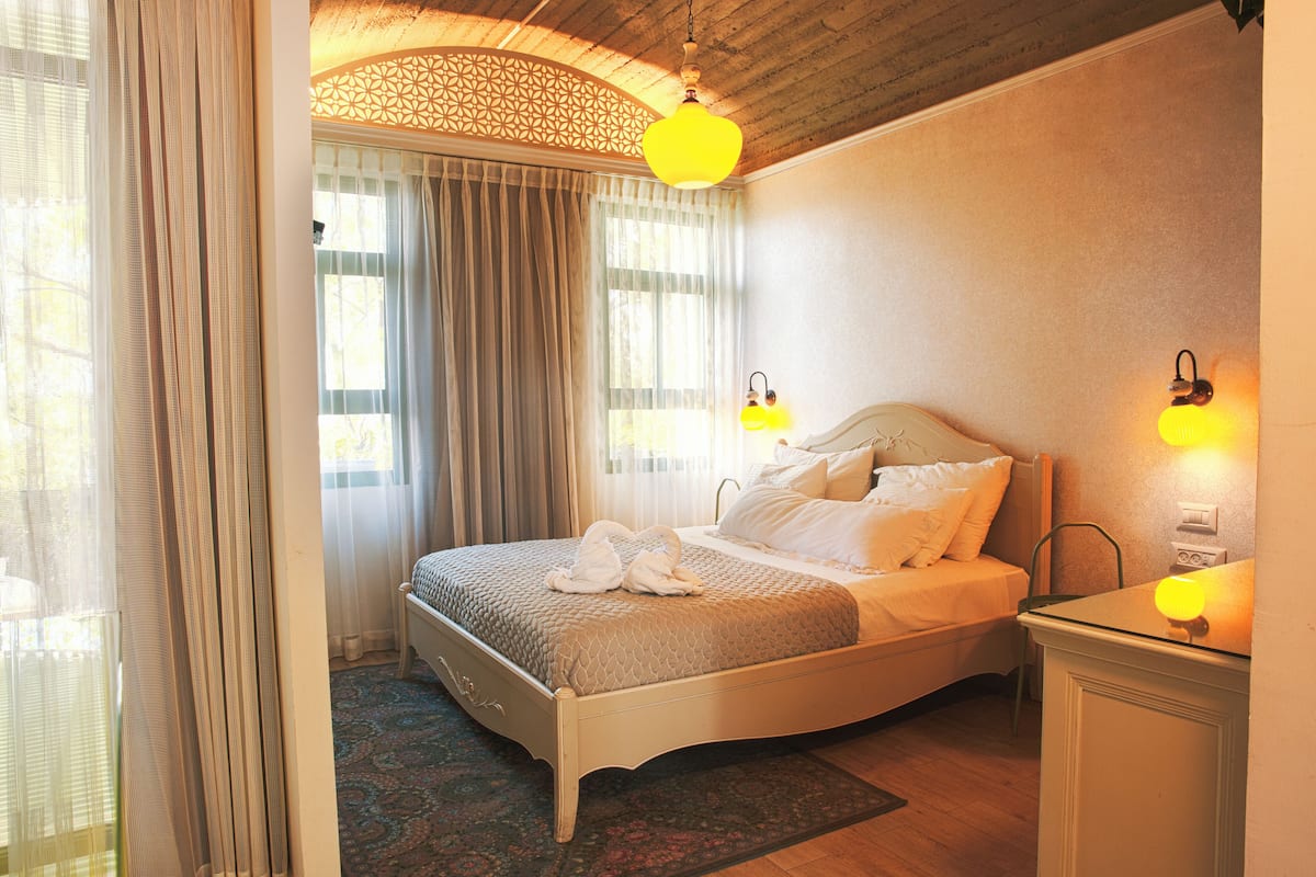 Quarto bem organizado com cama, luminárias de cabeceira e mesa de apoio.