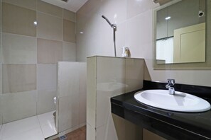 Casa de banho com uma pia branca, espelho e chuveiro.