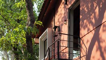 Um edifício com fachada vermelha, uma janela e uma árvore com folhas verdes.