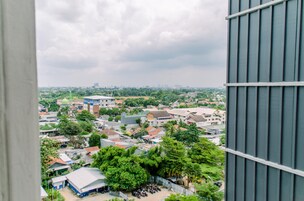 Paisagem urbana com edifícios residenciais, árvores e uma construção alta ao longe.
