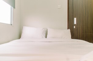 Cama bem arrumada com lençóis brancos em quarto com porta de madeira e janela.
