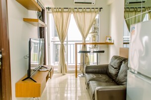 Sala de estar com televisão, sofá de couro e geladeira.
