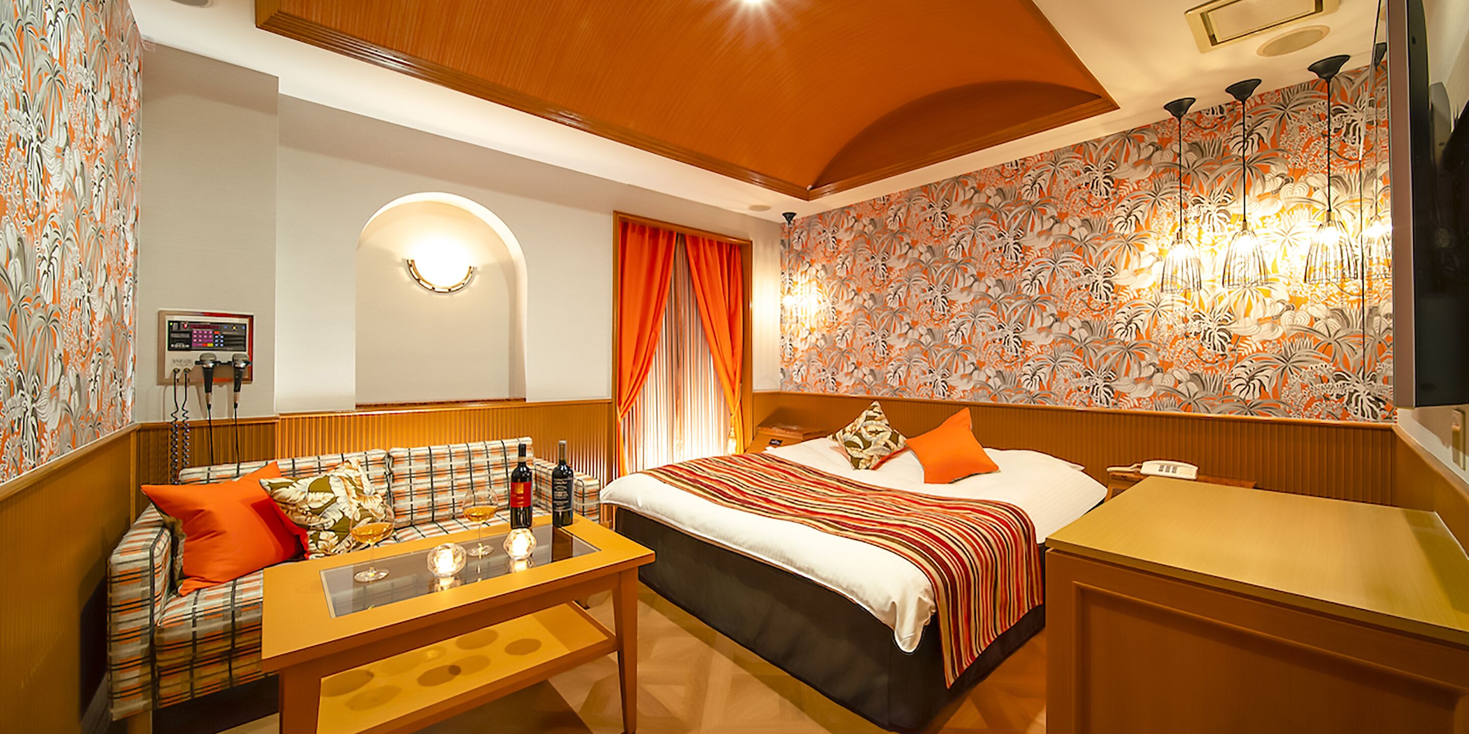 Quarto de hotel com cama, sofá, mesa e televisão.