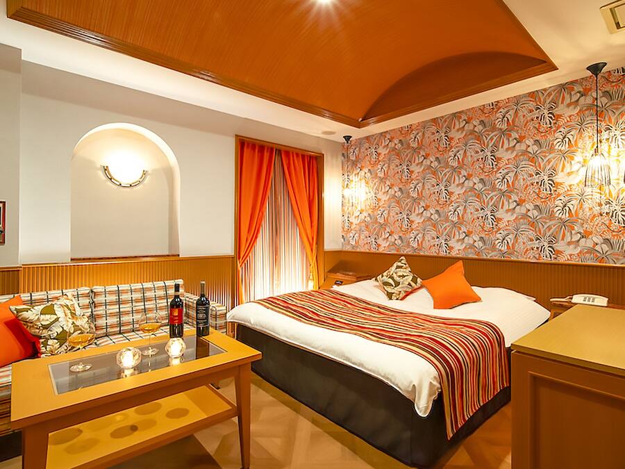 Quarto de hotel com cama, sofá, mesa e televisão.