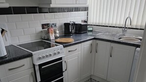 Uma cozinha moderna com armários brancos, bancada preta, fogão, forno e pia.
