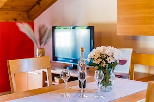 Mesa de jantar com uma garrafa, duas taças de vinho e um vaso de flores.