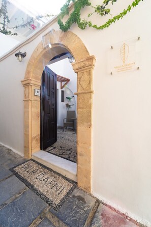 Uma entrada com arco de pedra, porta preta e tapete.