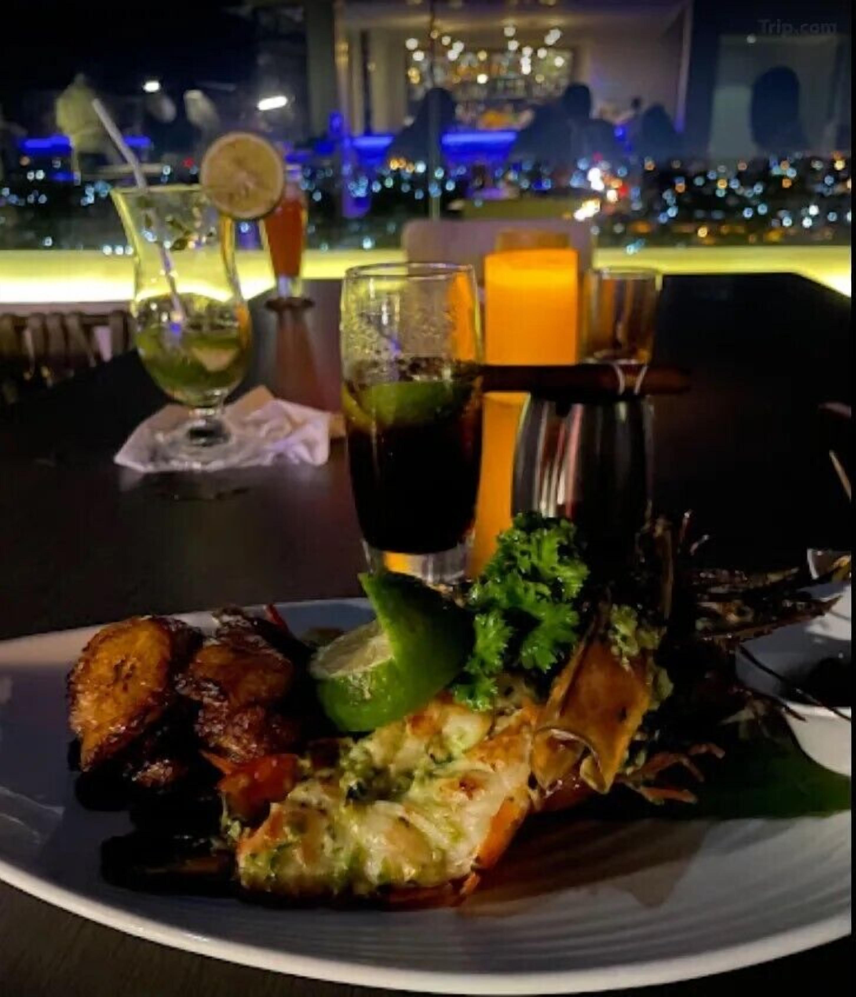 Uma mesa de jantar com prato de comida, bebidas e uma vela.