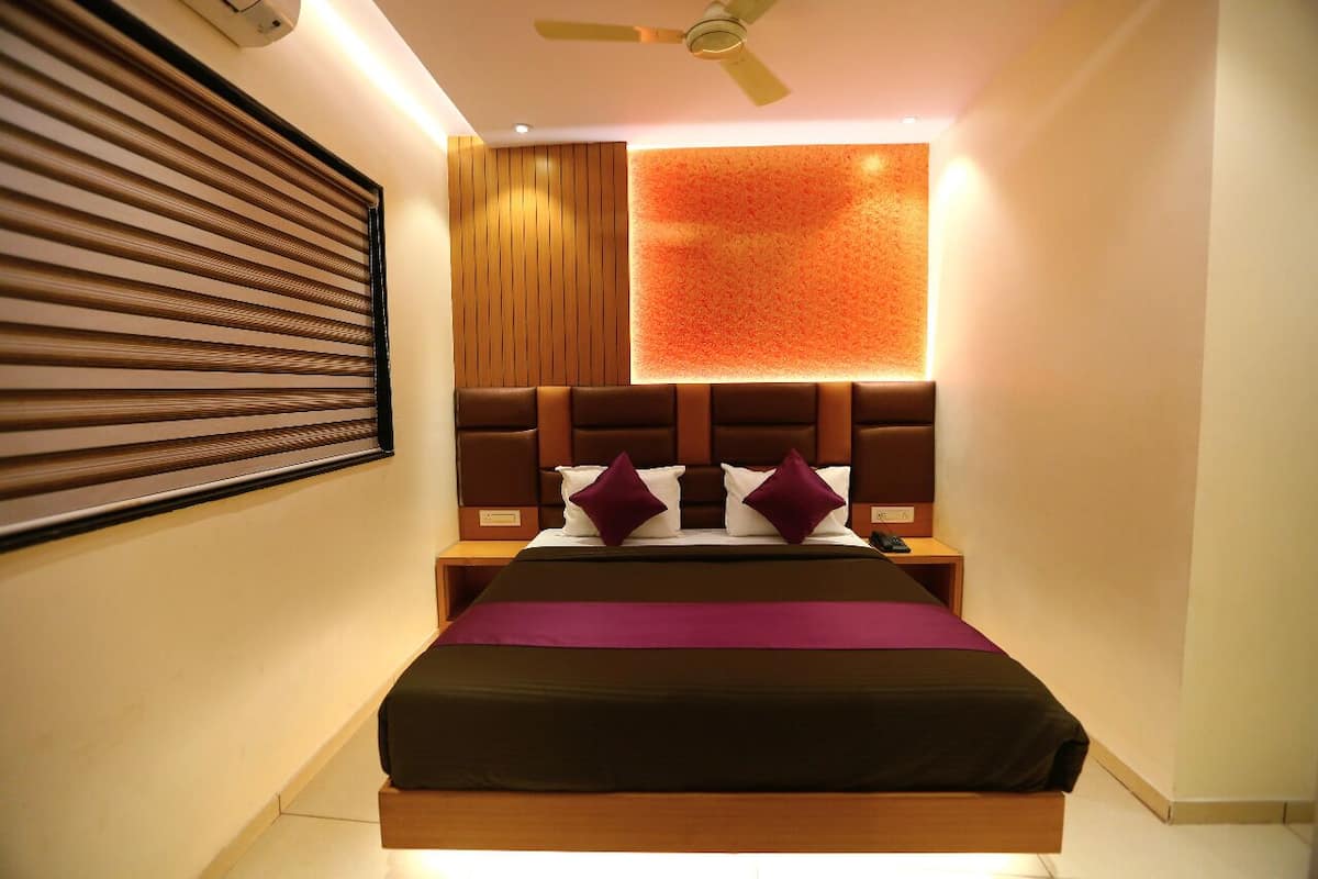 Quarto de hotel moderno com uma cama grande, um ventilador de teto e um candeeiro fixado na parede.