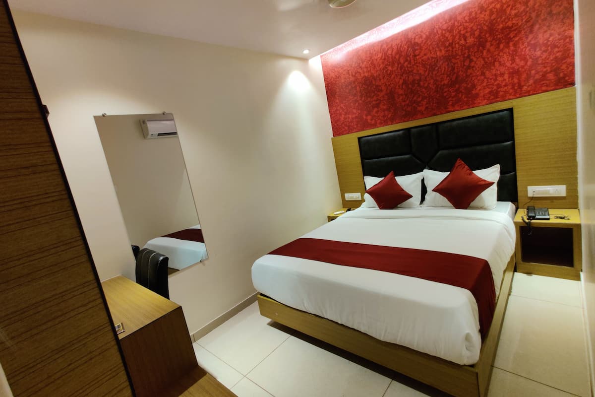 Quarto de hotel com uma cama grande, uma mesa de cabeceira com telefone e um espelho.