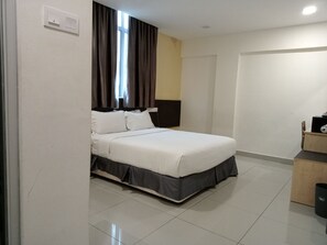 Quarto de hotel moderno com uma cama bem arrumada, mesa de cabeceira, luminária e armário.