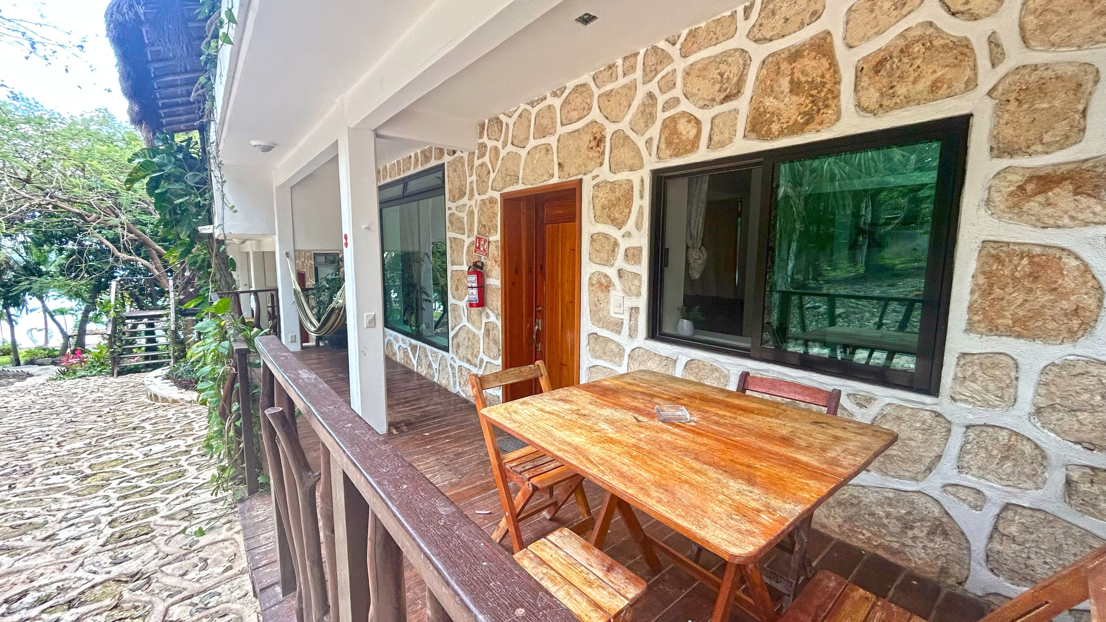 Um edifício de pedra com um deck de madeira, uma mesa e cadeiras.