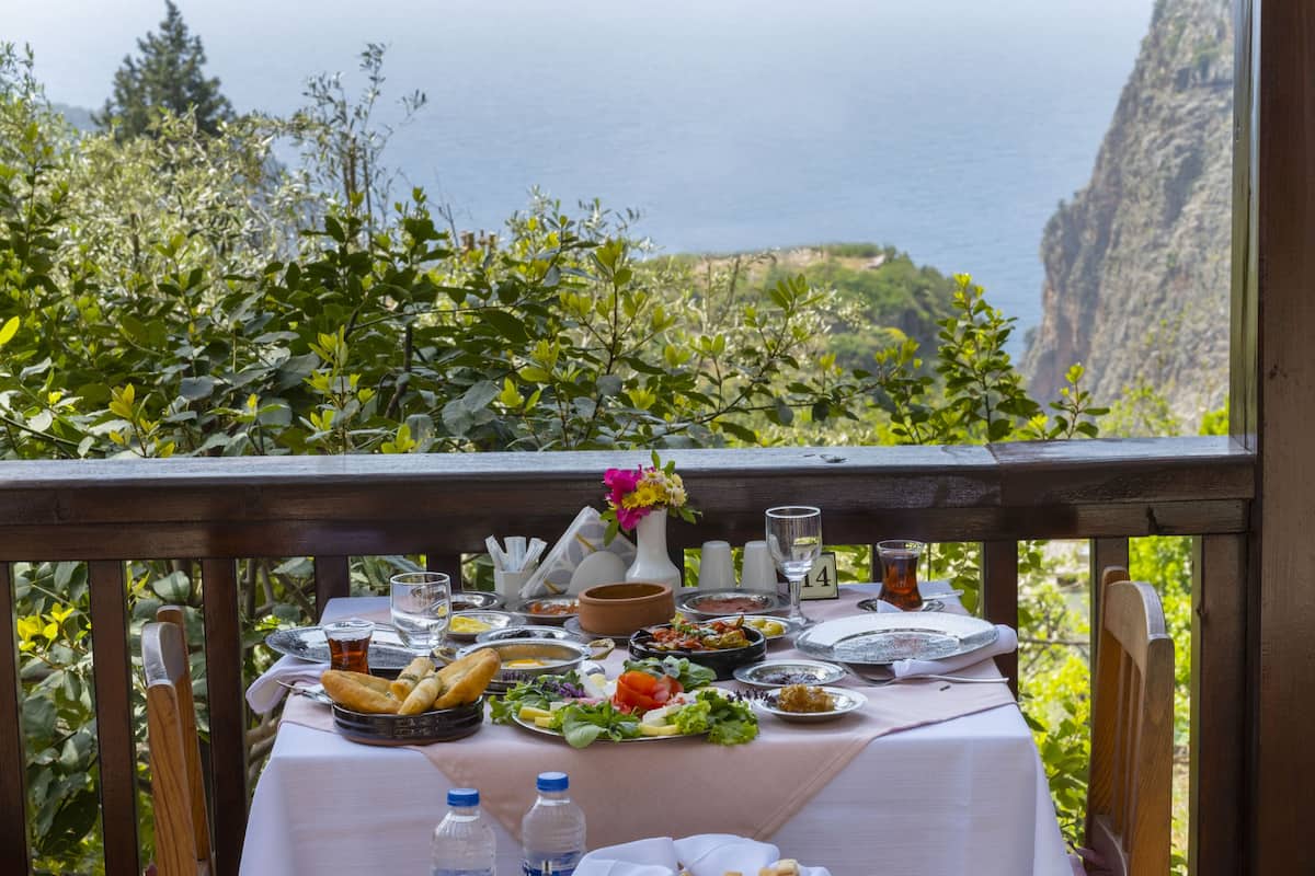 Mesa posta para refeição, vista para o mar e falésias.