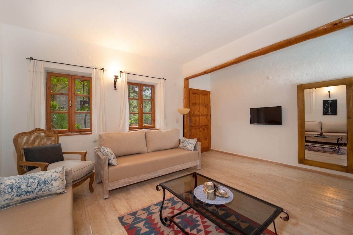 Uma sala de estar com sofá, poltronas, mesa de centro e televisão.