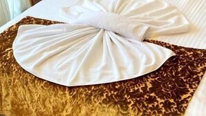 Cama bem arrumada com travesseiro grande em forma de laço e colcha estampada.