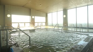 Piscina interior com água cristalina, grades de metal e amplas janelas que permitem entrada de luz natural.
