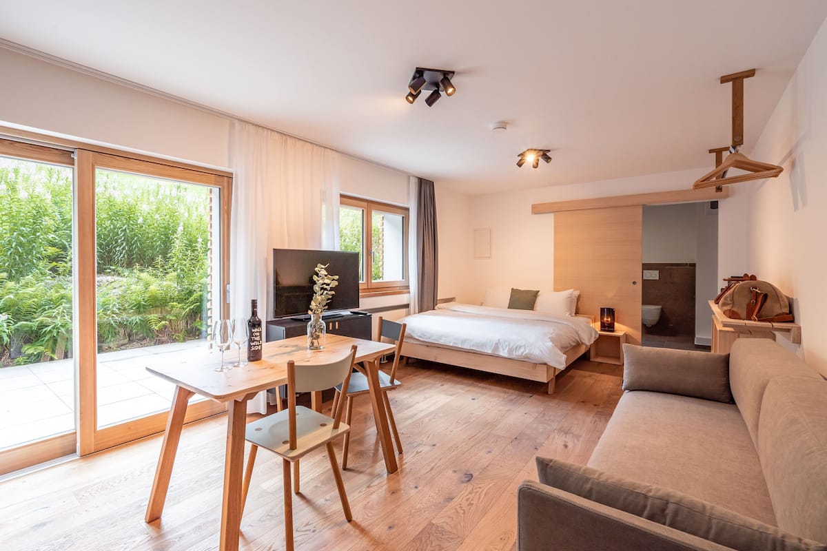 Quarto moderno com cama, mesa de cabeceira e televisão.