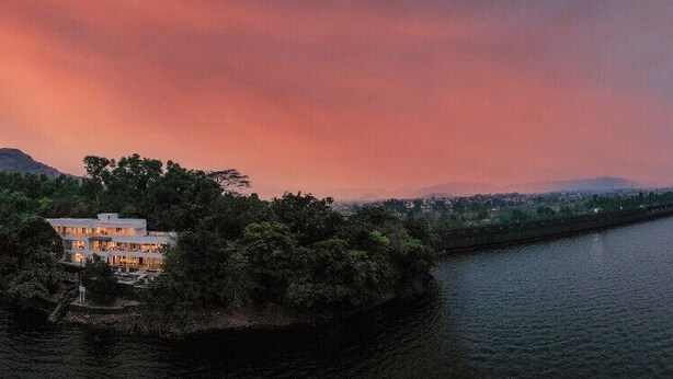 Uma casa numa ilha, cercada por água, com uma montanha ao fundo.