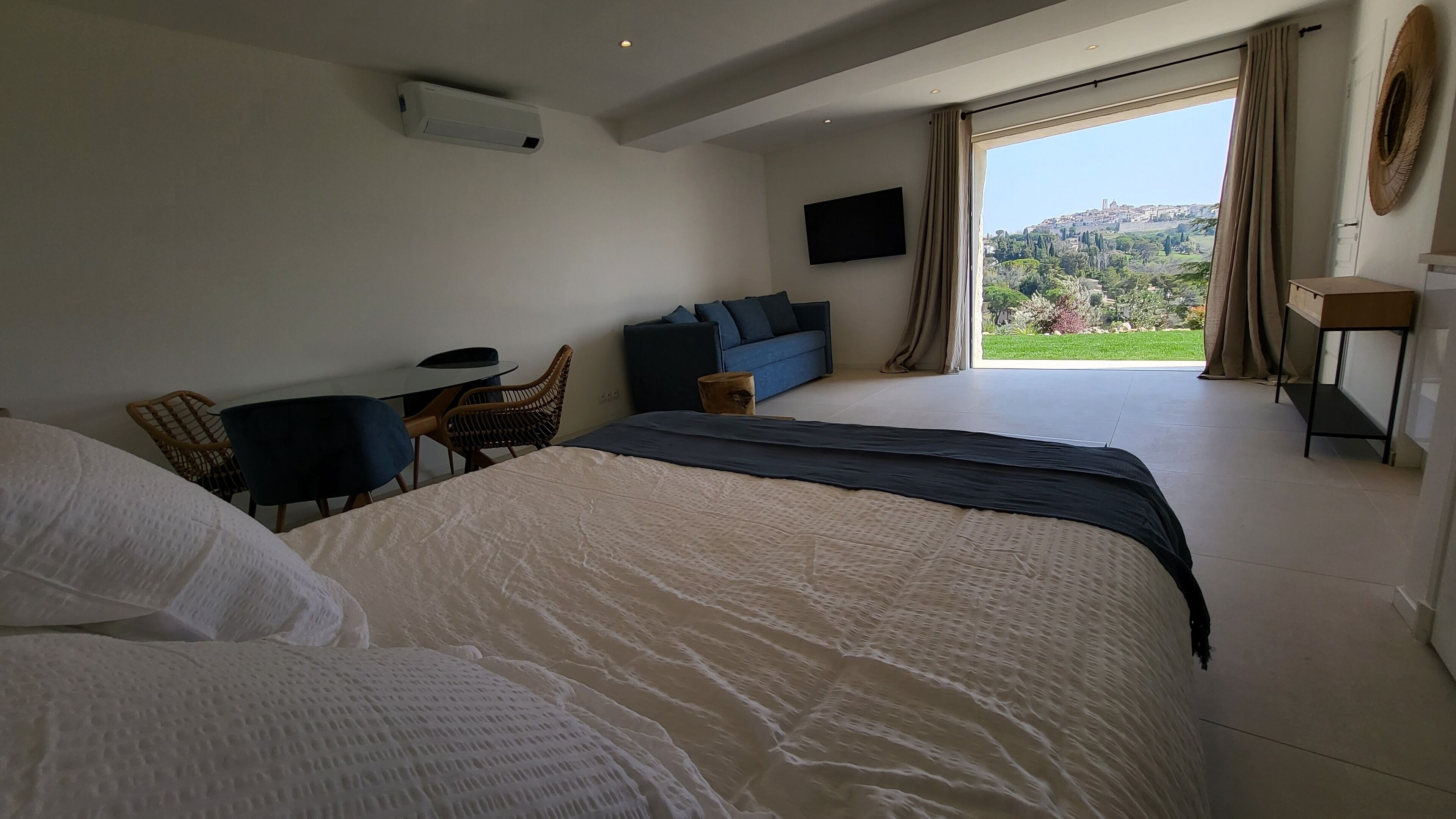 Quarto com uma cama grande, um sofá, uma mesinha e uma televisão.