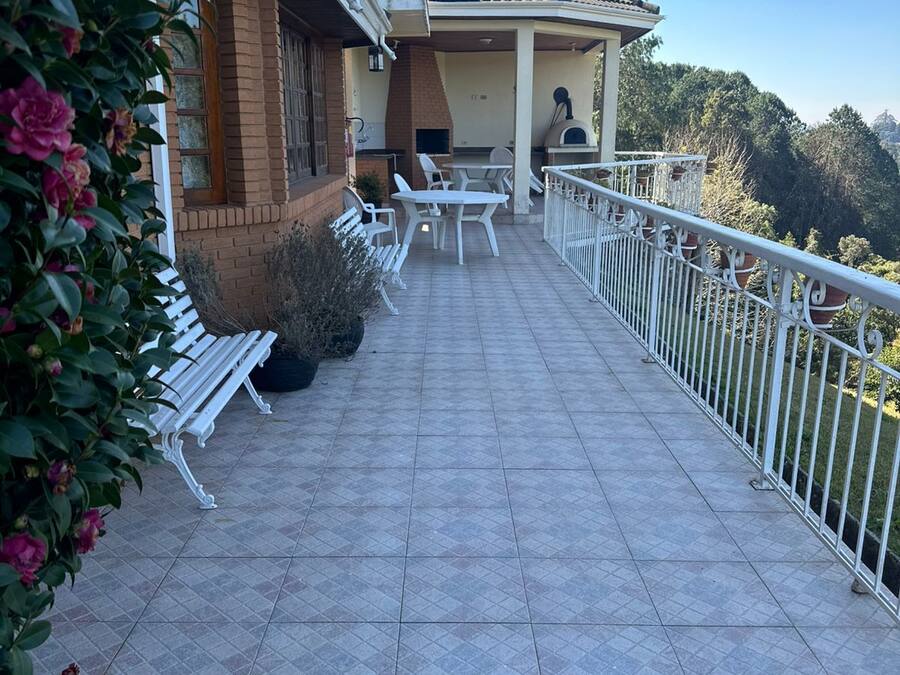 Uma varanda com piso de azulejos, móveis brancos e corrimão branco.