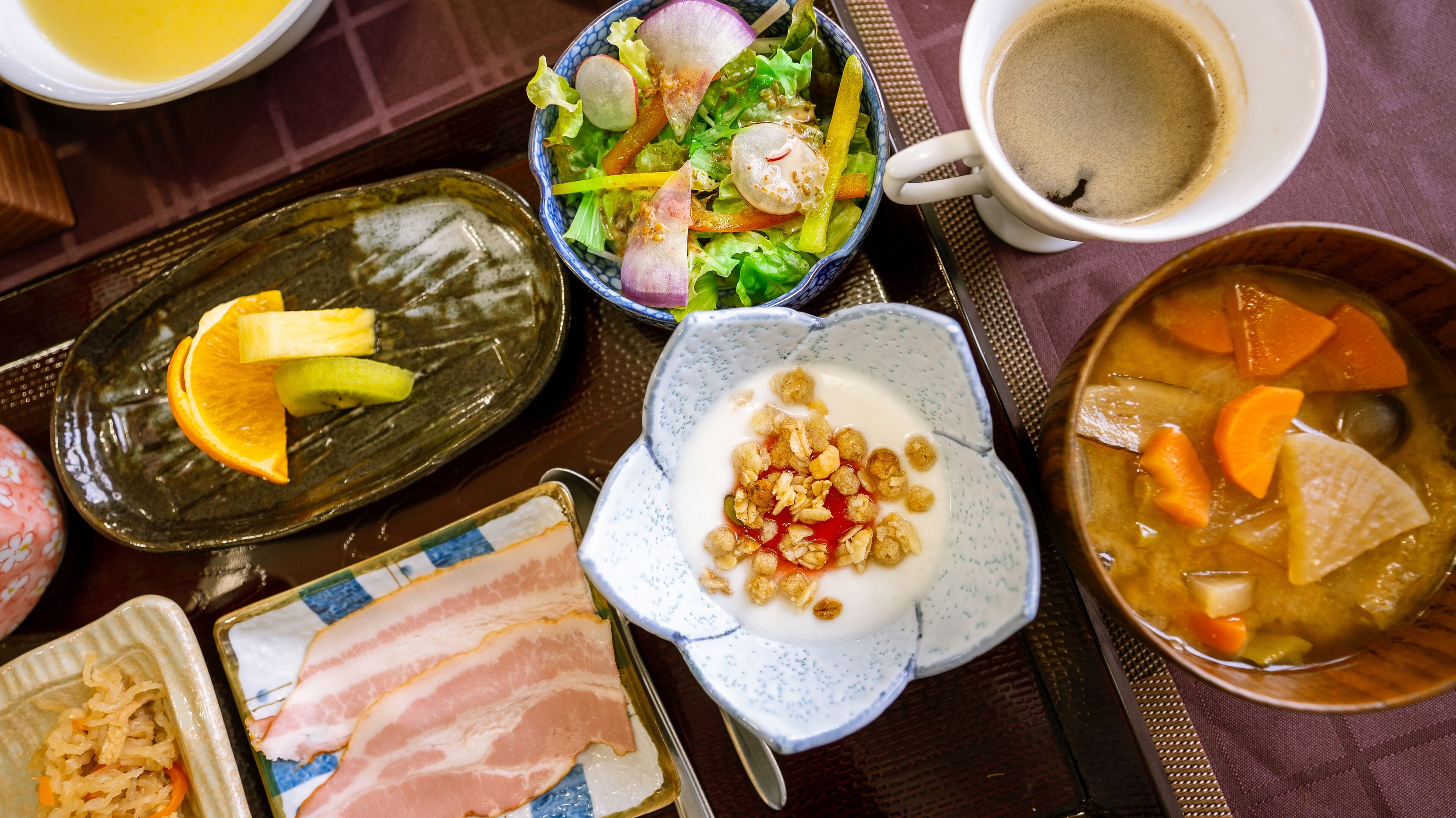 Uma mesa com diversos pratos, incluindo salada, sopa e porções de carne.