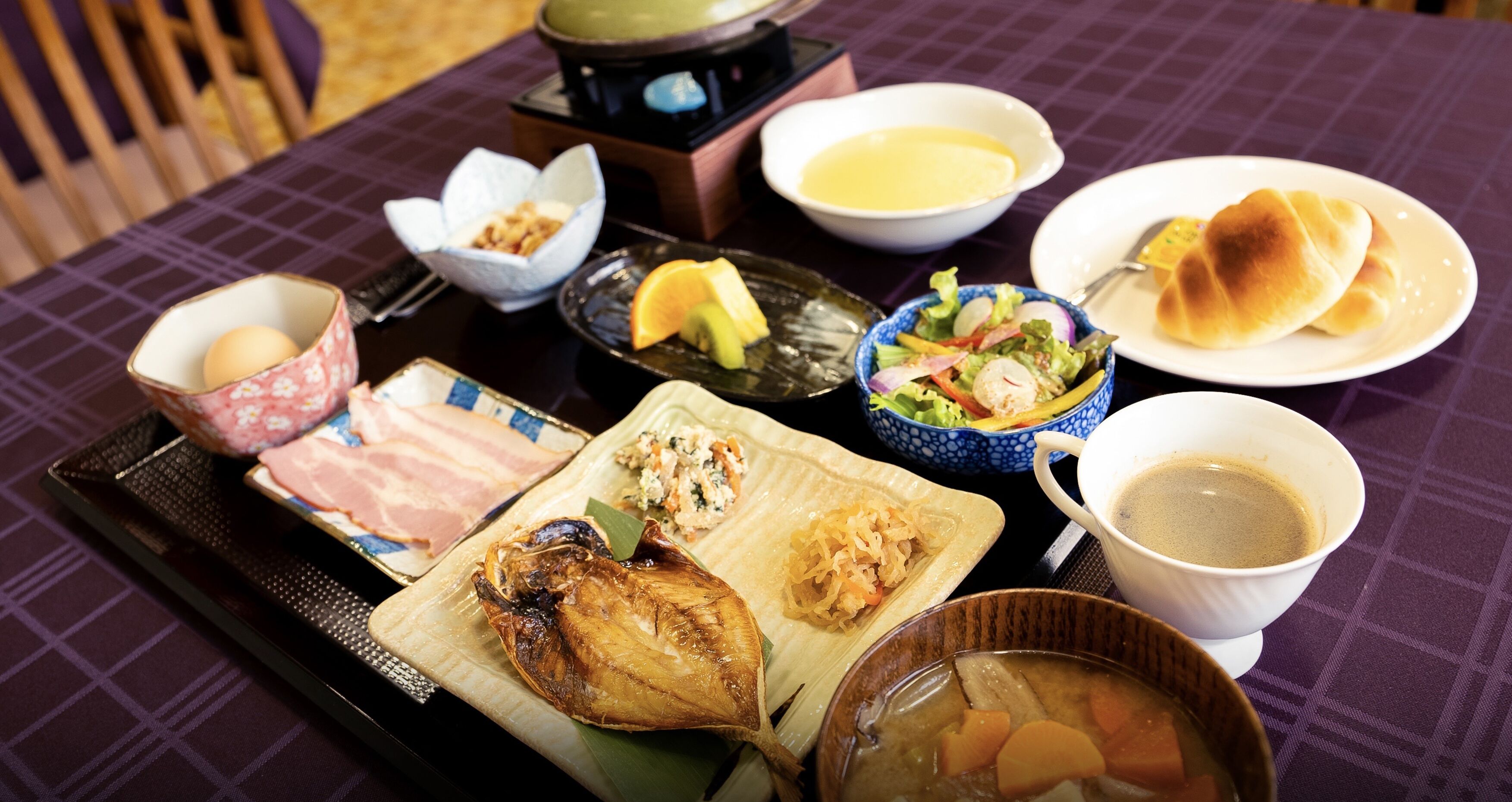 Uma mesa de jantar com diversos pratos, incluindo peixe, sopa, salada e pão.